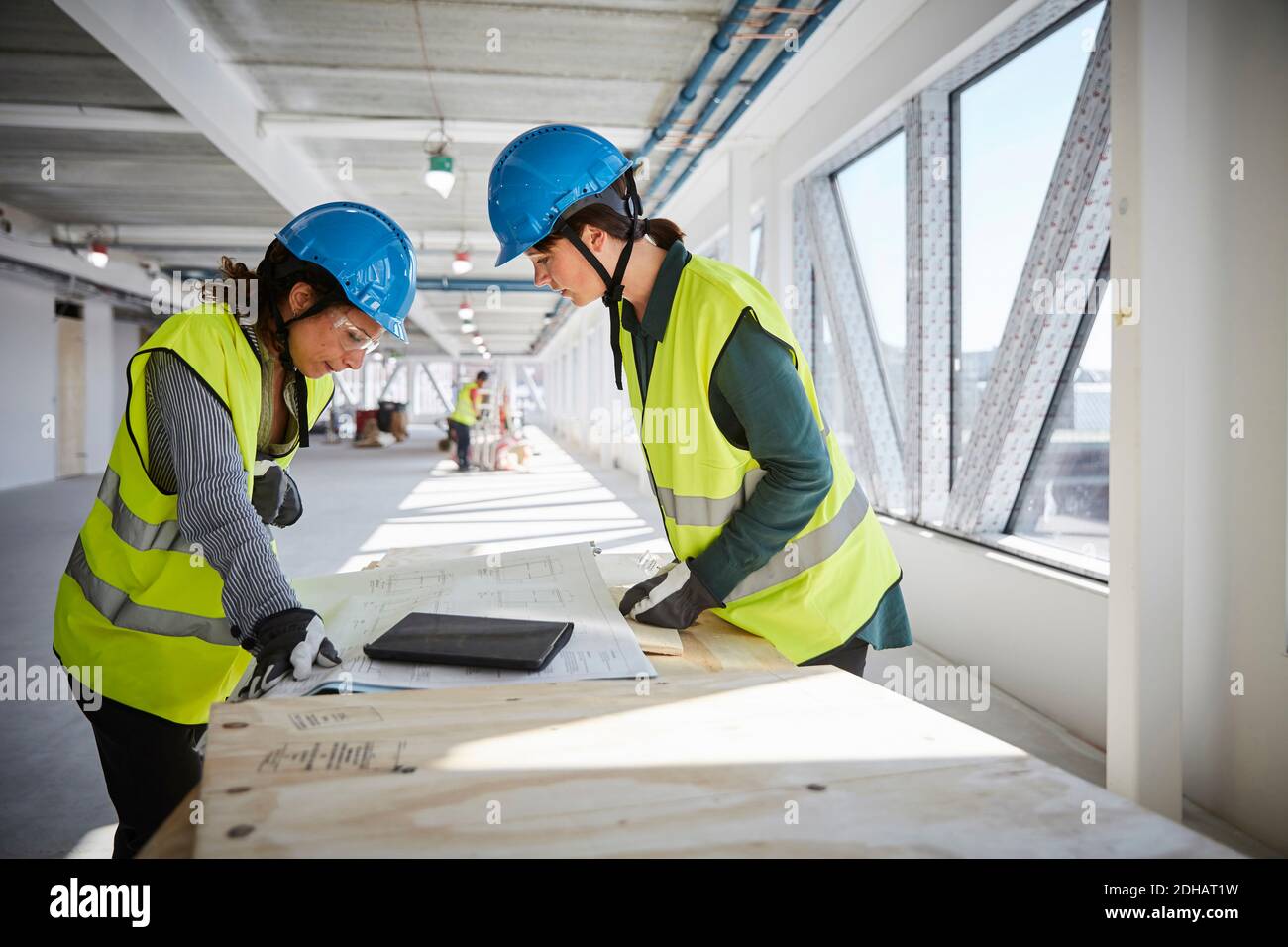 Side view of female engineers discussing over blueprint at construction ...