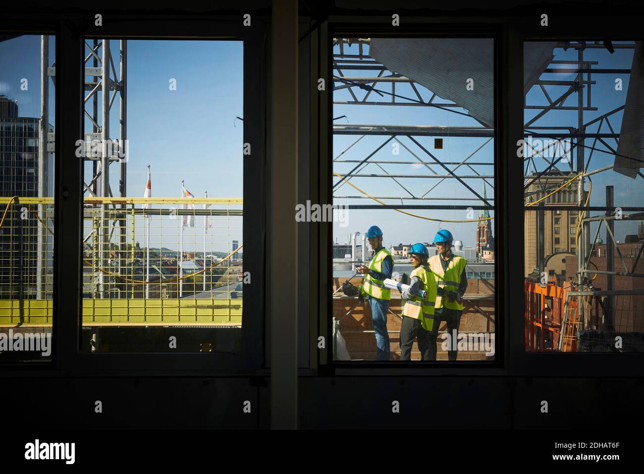 Male and female architects seen through window at construction site ...