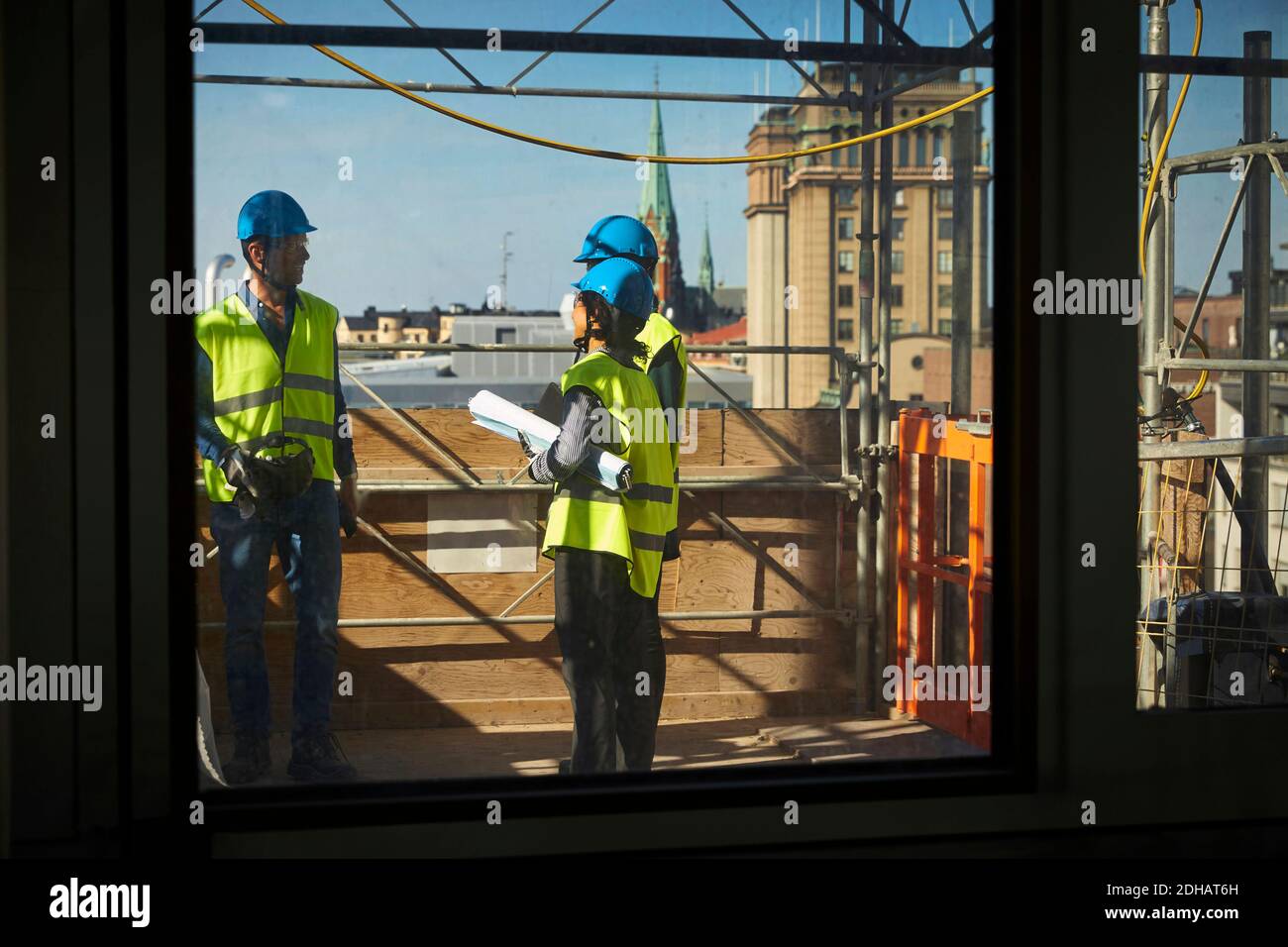 Male and female engineers seen through window at construction site ...