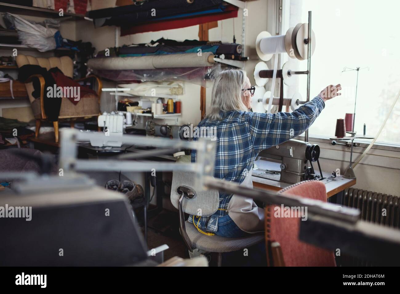 Senior owner using sewing machine at table in workshop Stock Photo - Alamy
