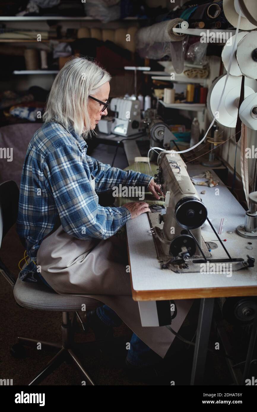 Senior owner using sewing machine at workshop Stock Photo - Alamy