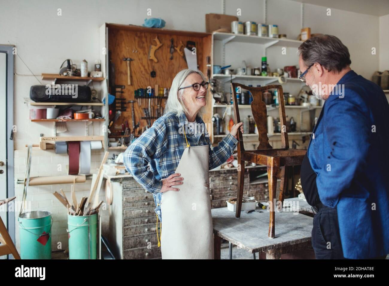 Smiling female owner showing wooden chair to customer at workshop Stock ...