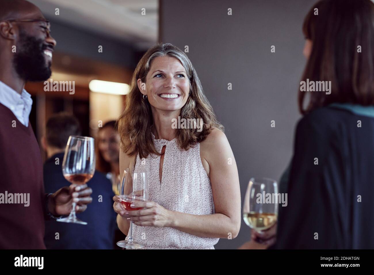 Smiling business people talking over drinks in office party Stock Photo ...