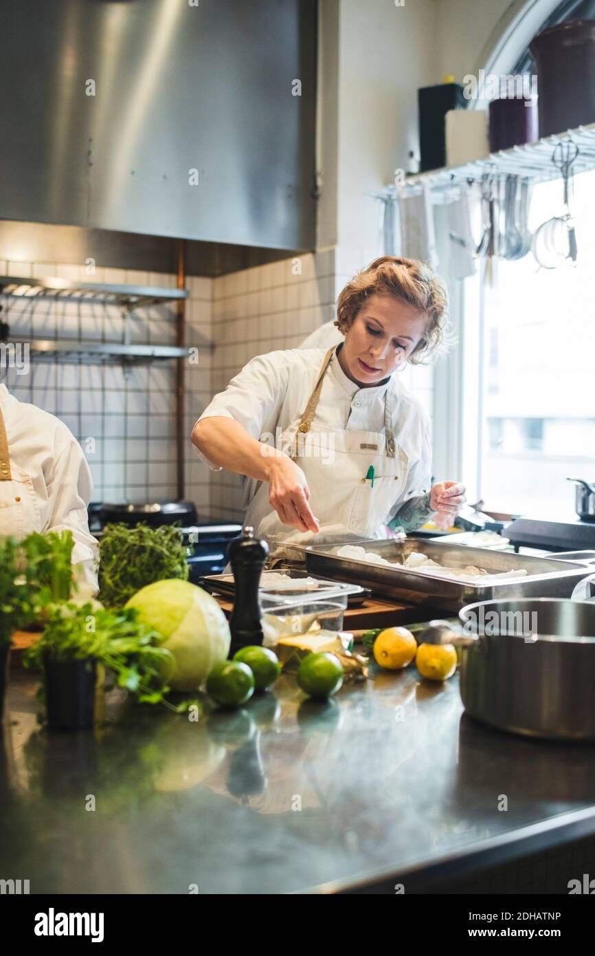 Female chef preparing food in tray at commercial kitchen Stock Photo ...