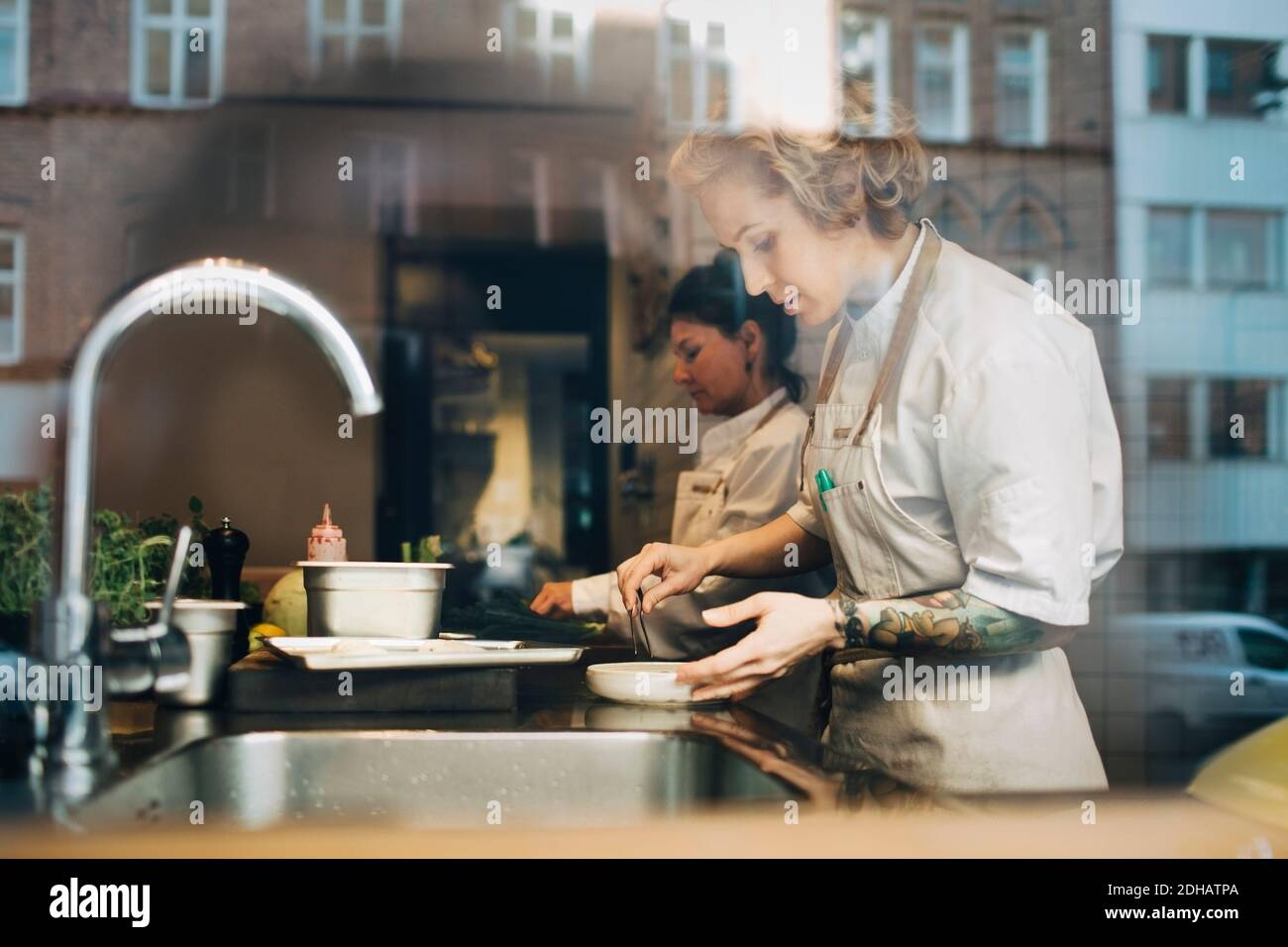 Side view of female chefs preparing food at counter in restaurant ...