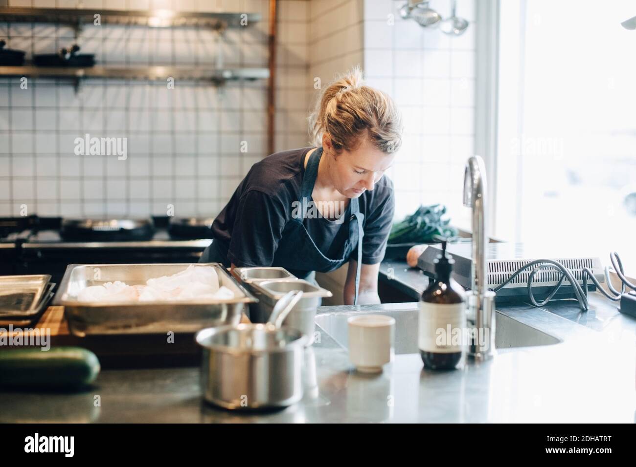 Mature female chef working by kitchen counter in restaurant Stock Photo ...