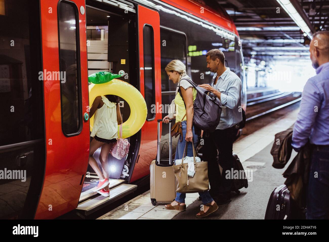 Family with luggage boarding train together at railroad station ...
