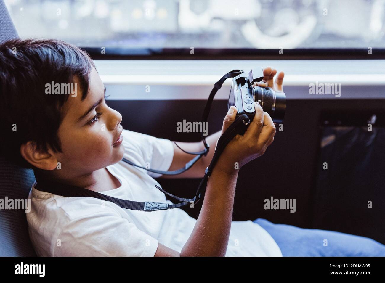 Boy photographing through camera while sitting in train Stock Photo - Alamy