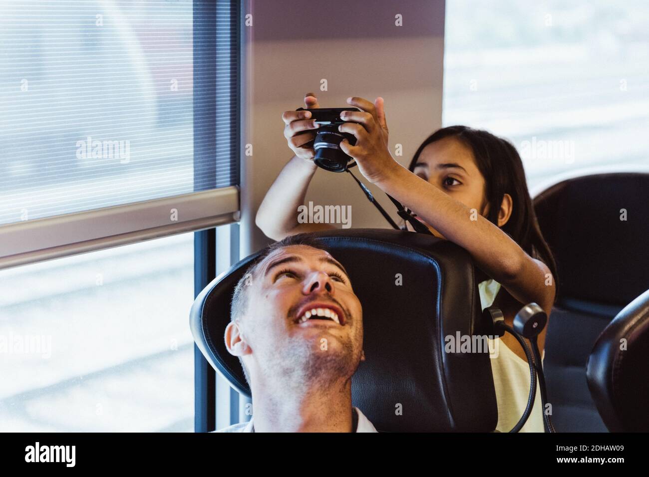 Girl photographing father with camera while sitting in train Stock ...