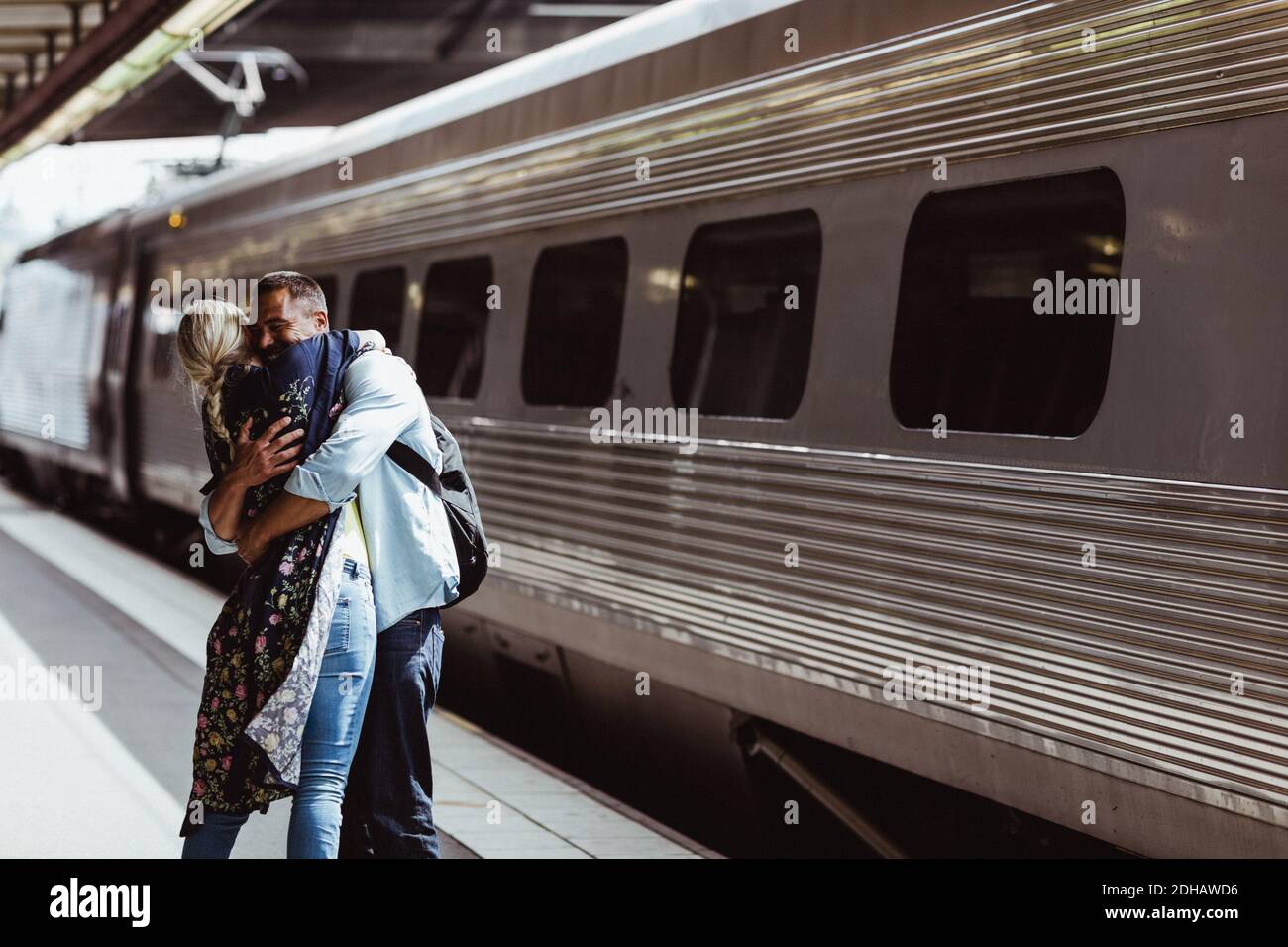 Loving couple embracing by train on railroad station platform at ...