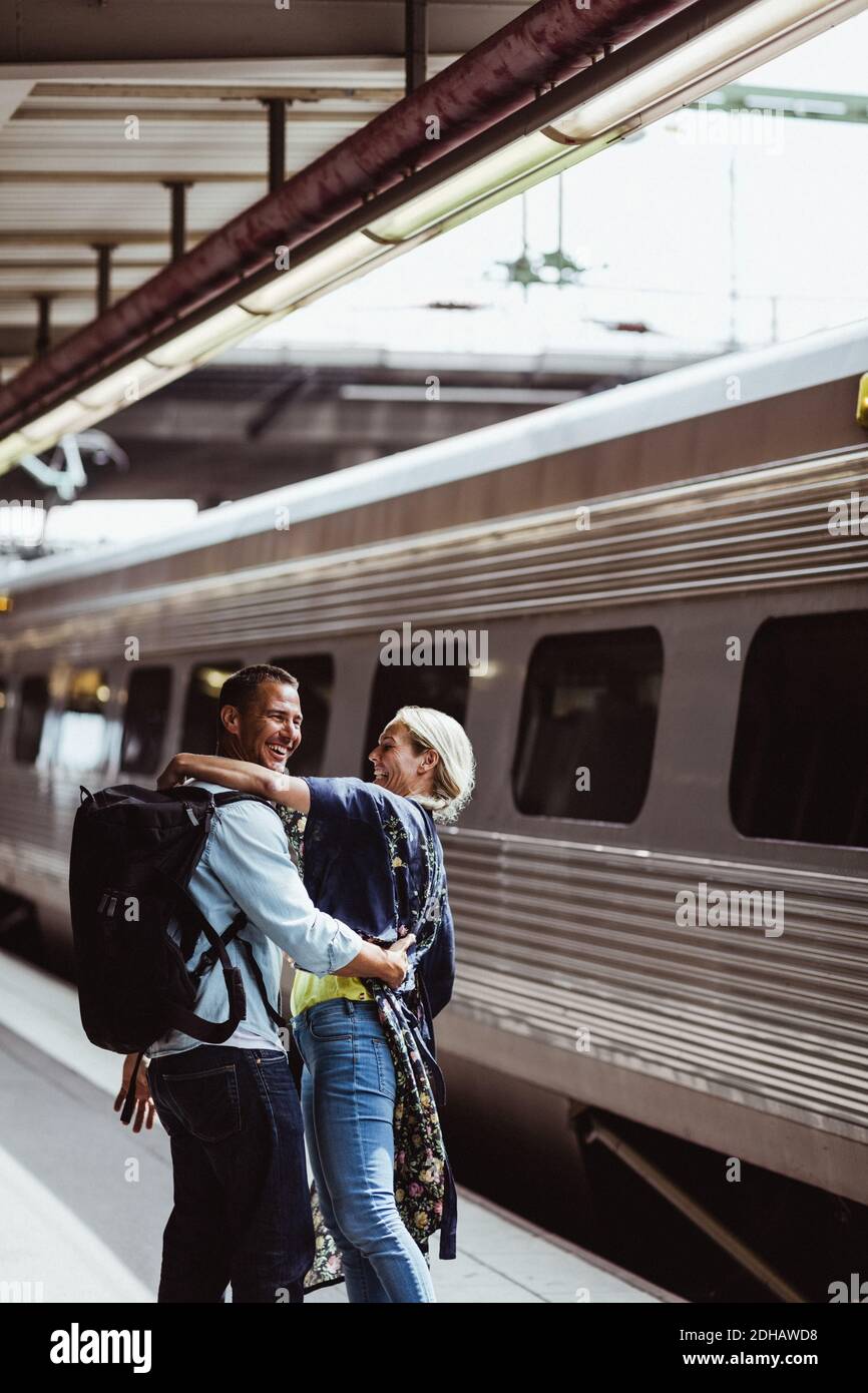 Happy couple embracing by train at railroad station Stock Photo - Alamy