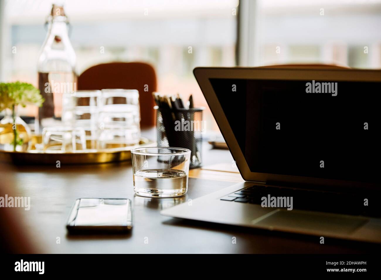 Laptop by drinking glass on conference table in board room Stock Photo ...