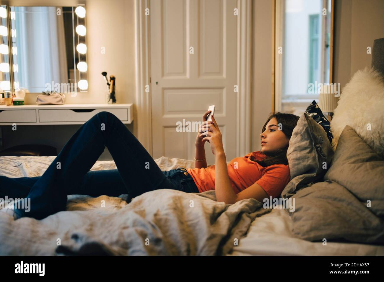 Girl using mobile phone while lying on bed at home Stock Photo - Alamy