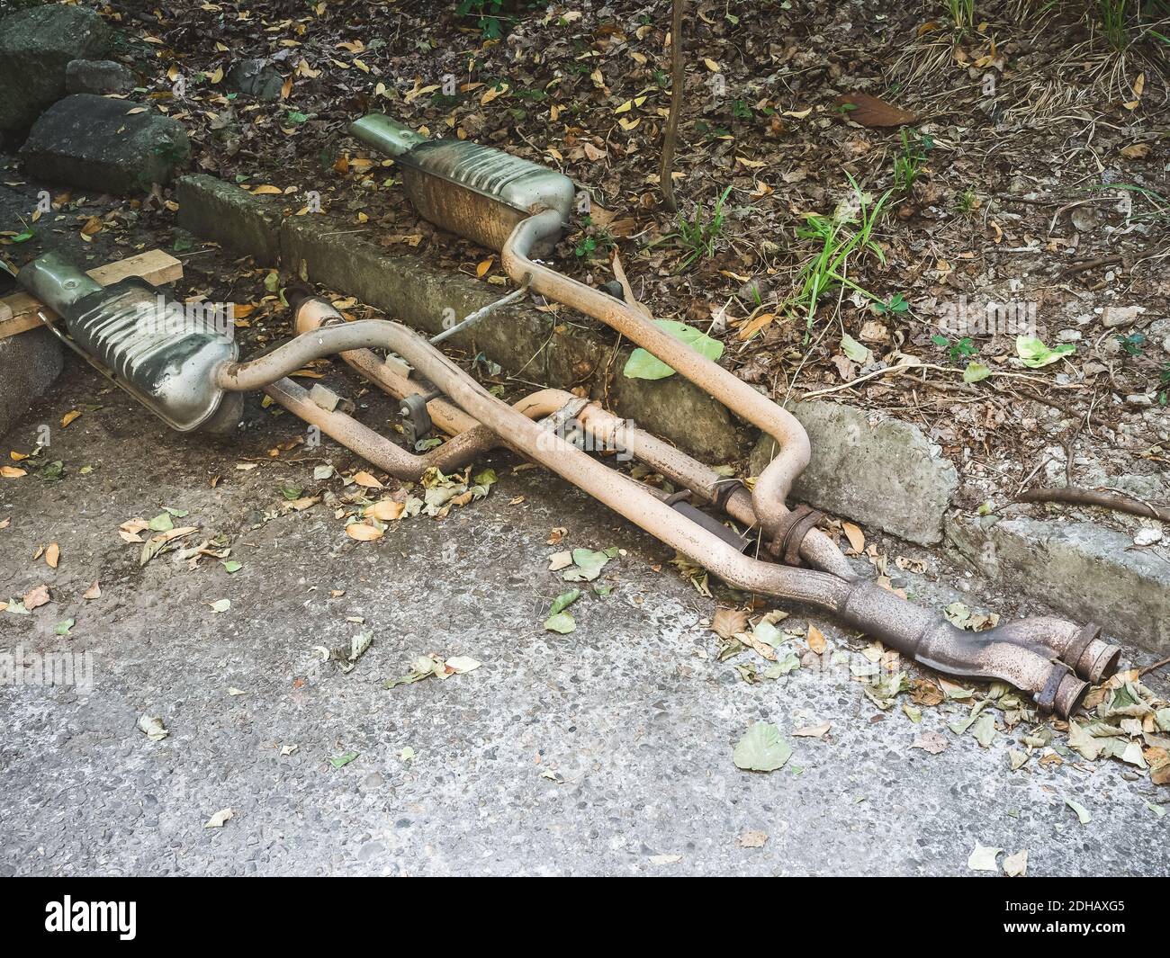 The old exhaust system from the car lies on the asphalt near the curb ...