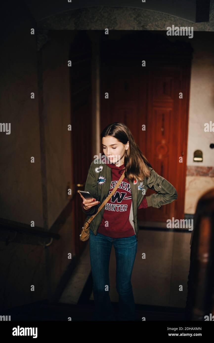 Girl using mobile phone while walking on steps Stock Photo - Alamy