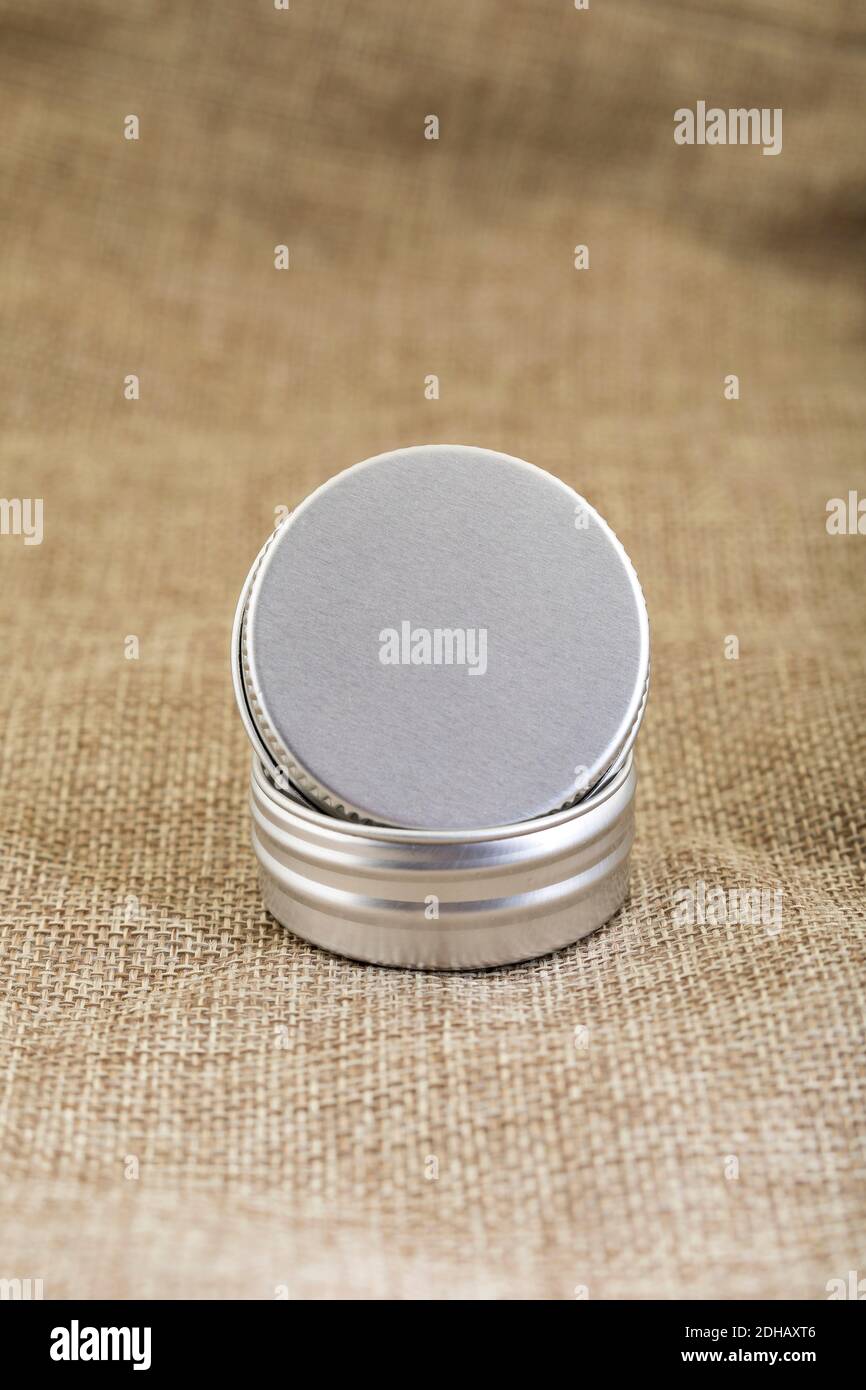 Medicine pill box in a shiny and silver round tin on cloth background ...