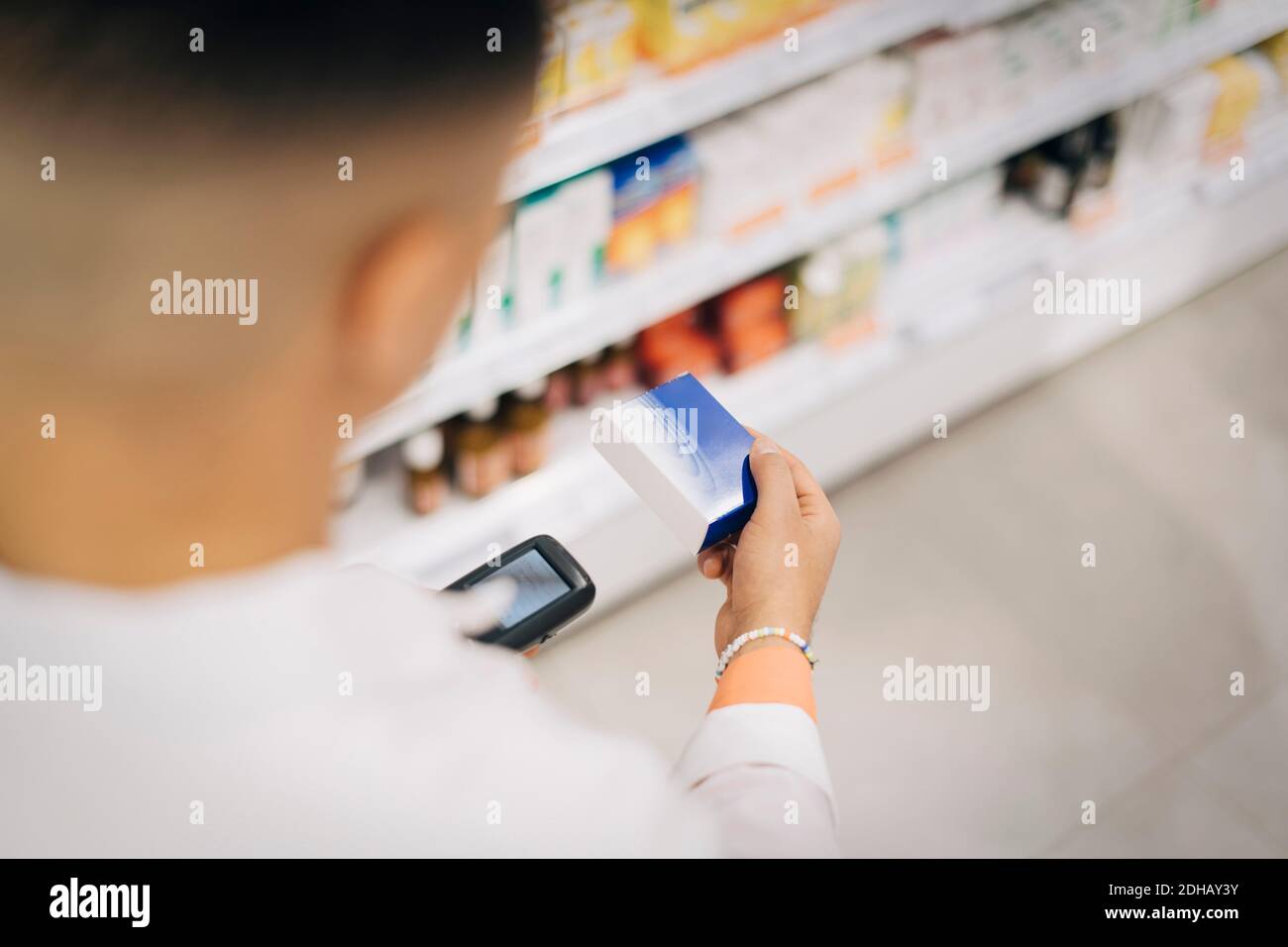High angle view of male pharmacist using bar code reader on medicine at ...