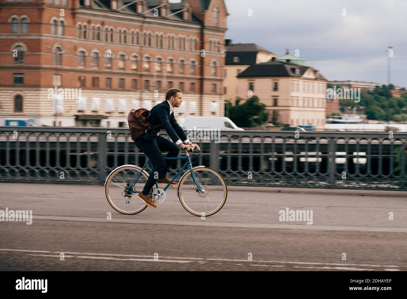 Side view of businessman riding bicycle on street in city Stock Photo ...