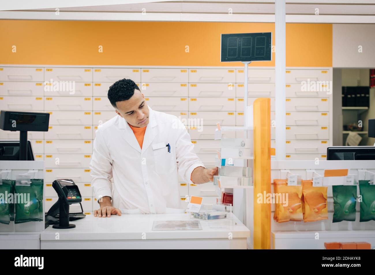 Confident pharmacist examining medicines at checkout in medical store ...