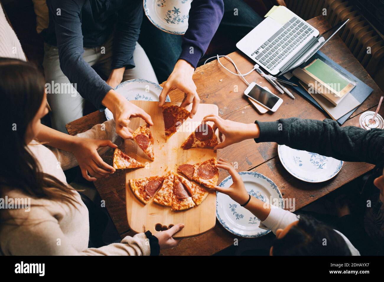 High angle view of friends taking slices of pizza at dining table Stock ...