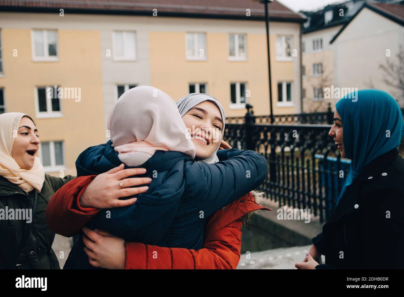 Happy Muslim women embracing by friends in city Stock Photo - Alamy
