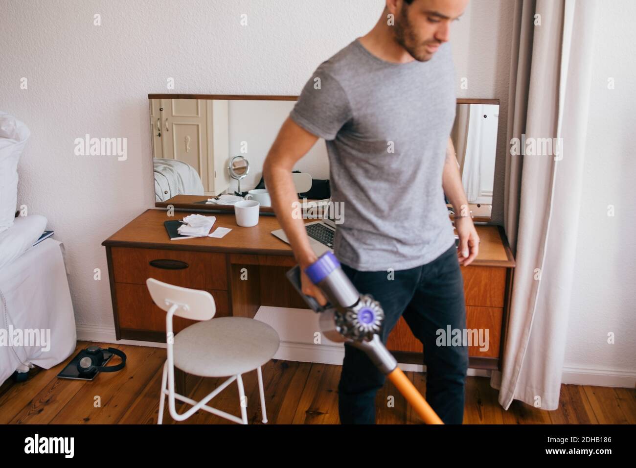 Mid adult man cleaning bedroom with vacuum cleaner Stock Photo - Alamy