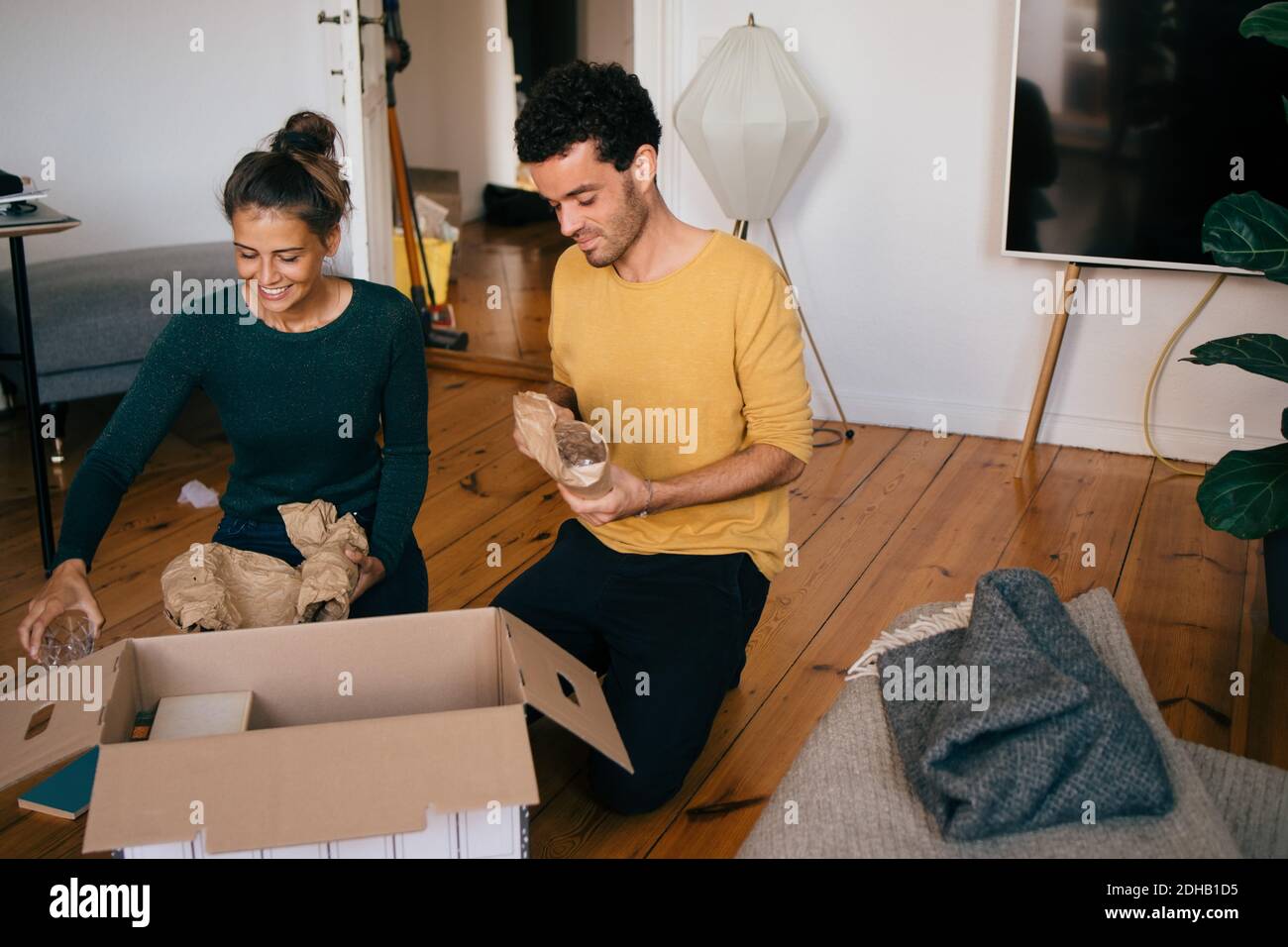 Couple removing glasses from box in living room at new home Stock Photo ...