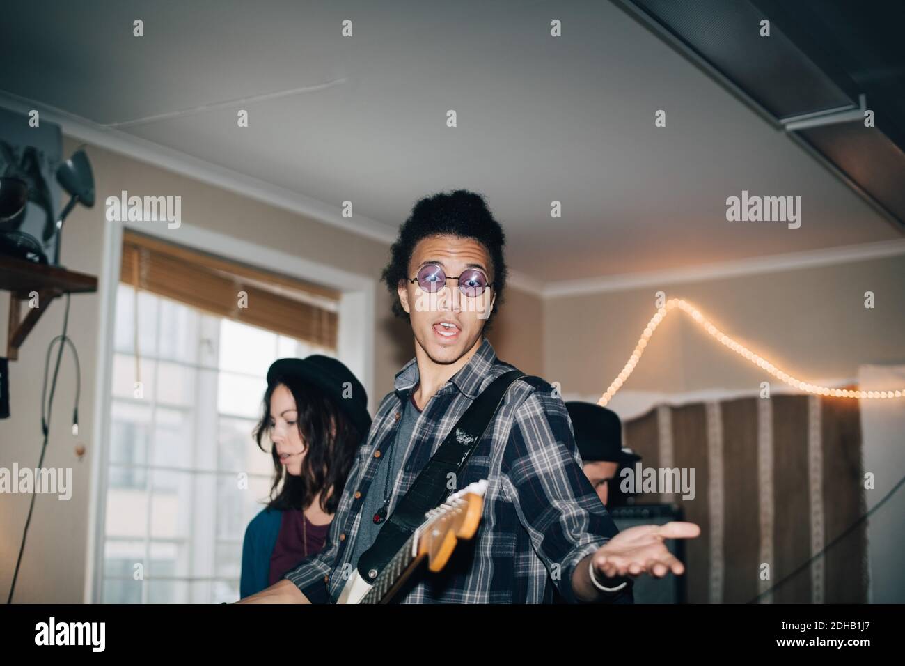 Male musician singing while playing instruments with friends at studio ...