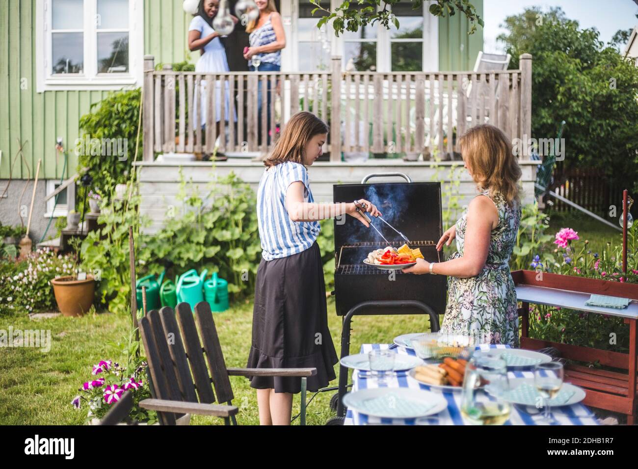 Mother and daughter preparing food on barbecue in backyard party Stock ...