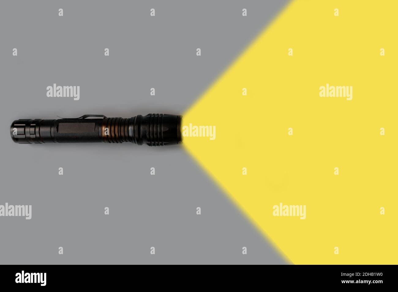 Flashlight turned on with yellow beam light on gray background with ...