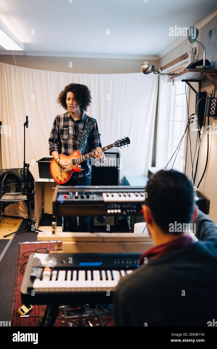 Male friends playing musical instruments at recording studio Stock ...
