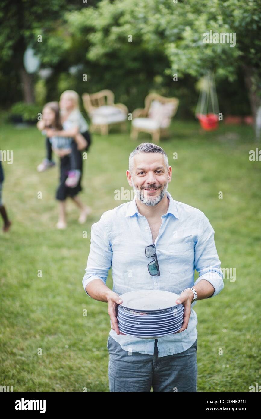 Portrait of happy man holding plates in backyard Stock Photo - Alamy