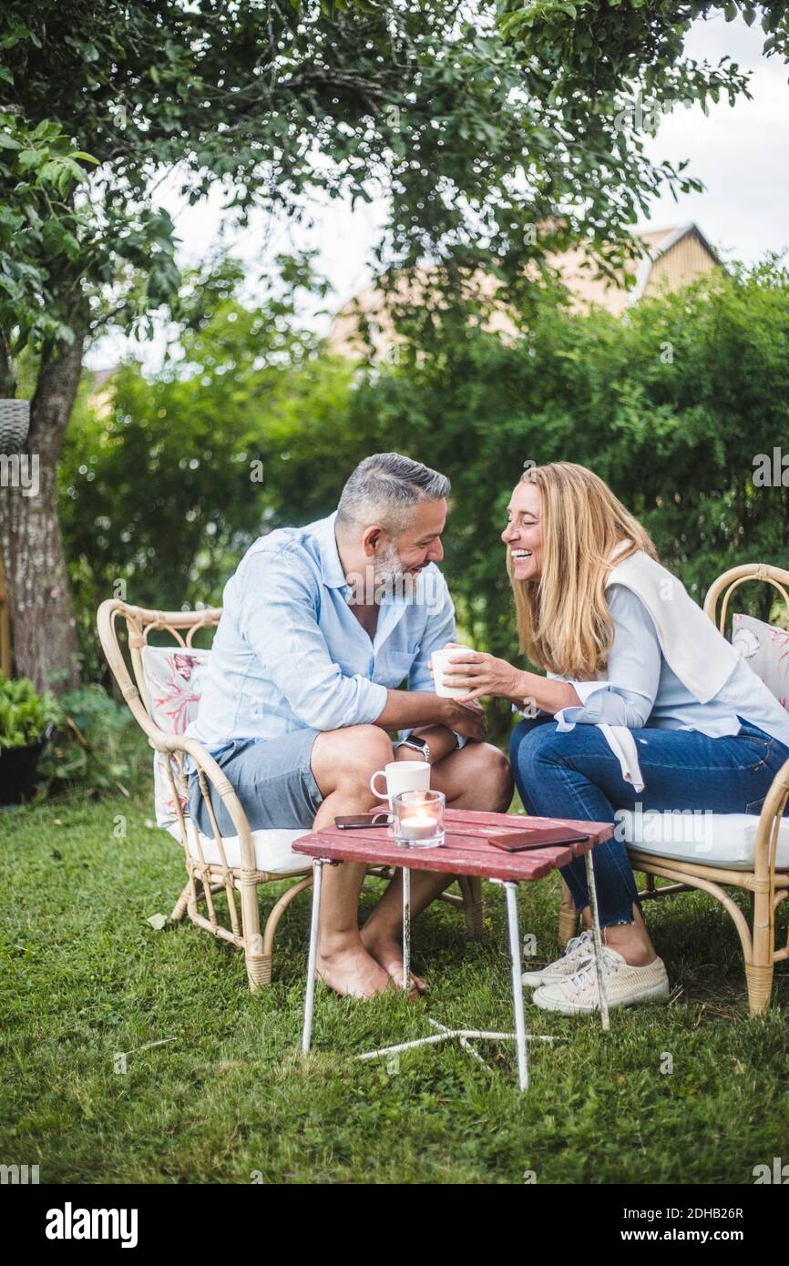 Smiling mature couple talking while sitting in backyard Stock Photo - Alamy