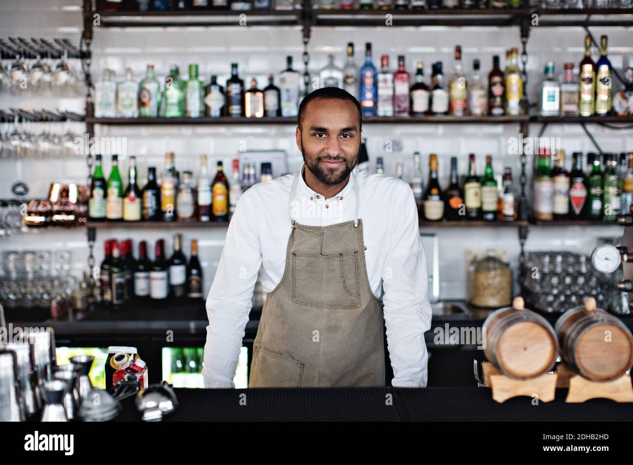Portrait of smiling male owner standing at checkout counter in ...