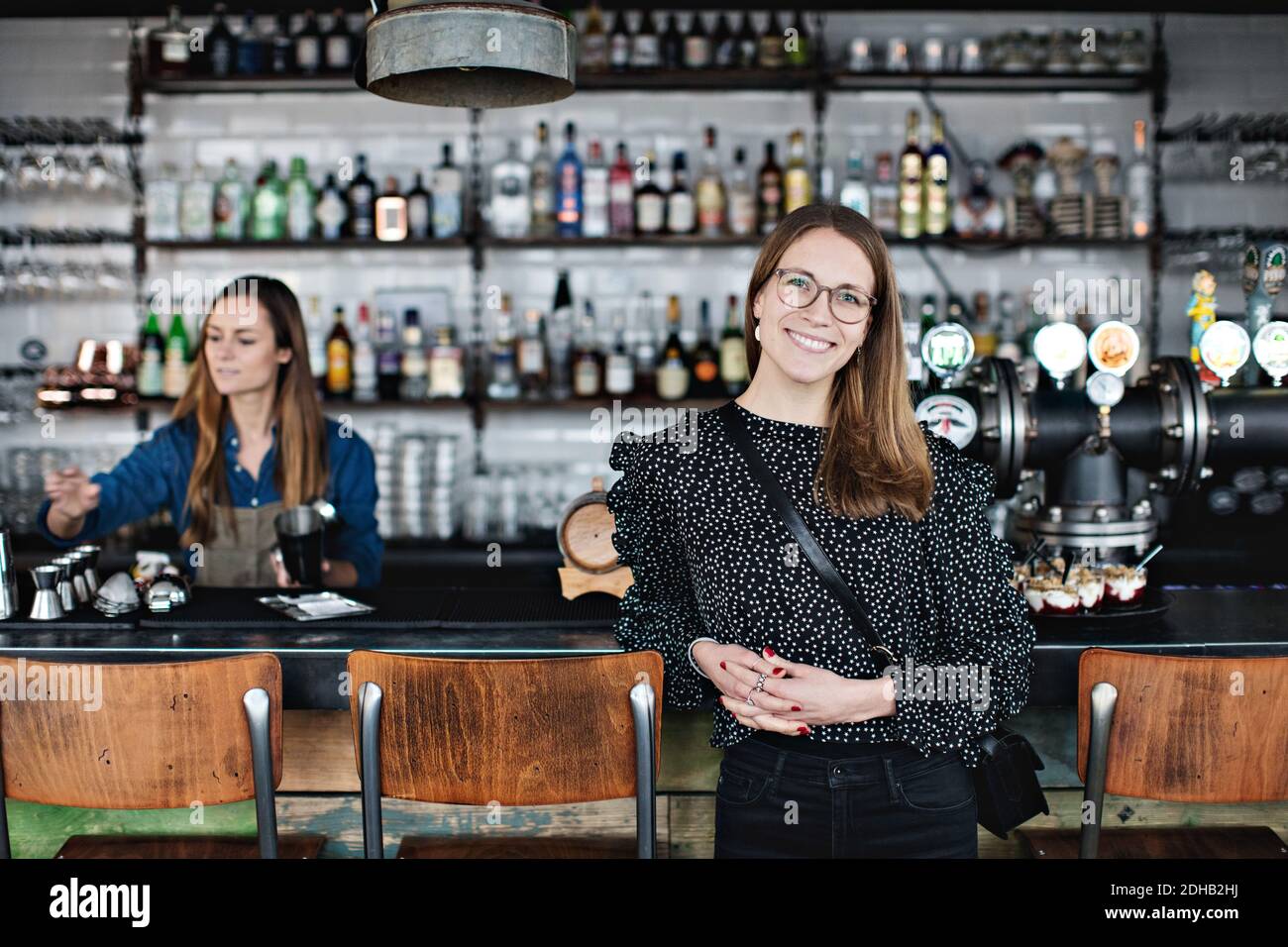 Portrait of smiling customer leaning at checkout counter with female ...