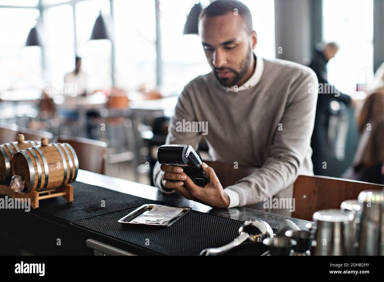 Customer using credit card reader at checkout counter in restaurant ...