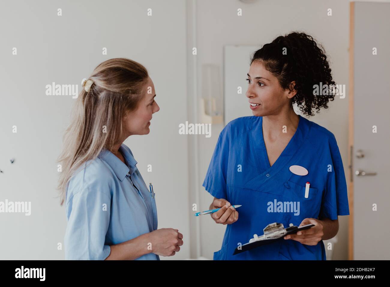 Female nurse discussing with doctor about medical report in hospital ...