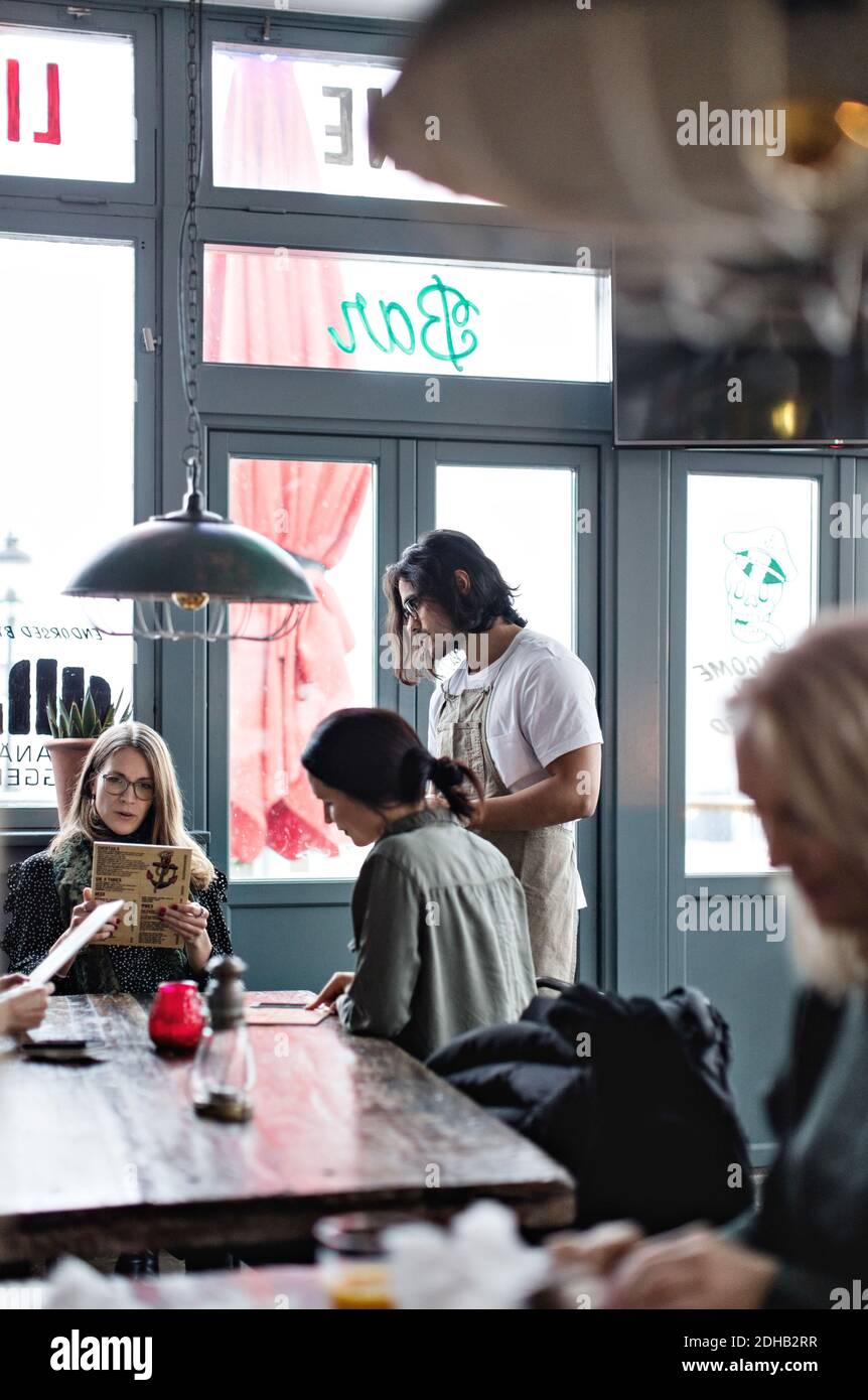 Woman ordering from menu to waiter while sitting at table Stock Photo ...