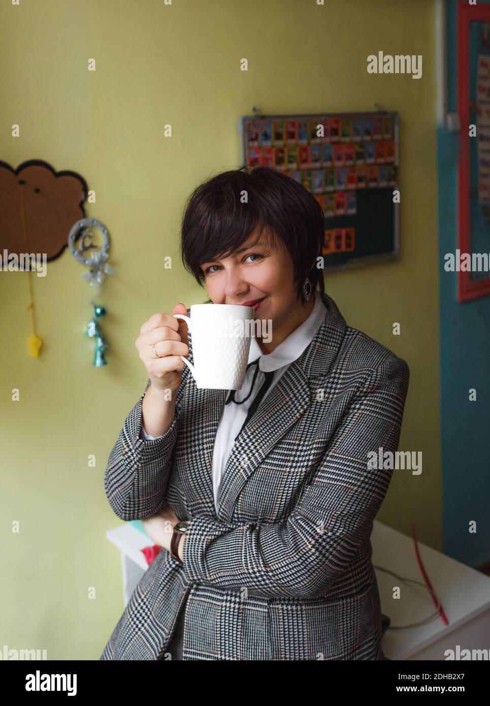 a girl teacher stands in the classroom and drinks tea in the absence of ...