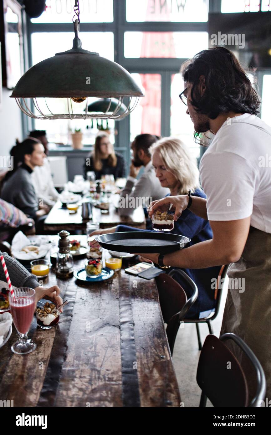 Waiter serving dessert to customers on dining table Stock Photo - Alamy