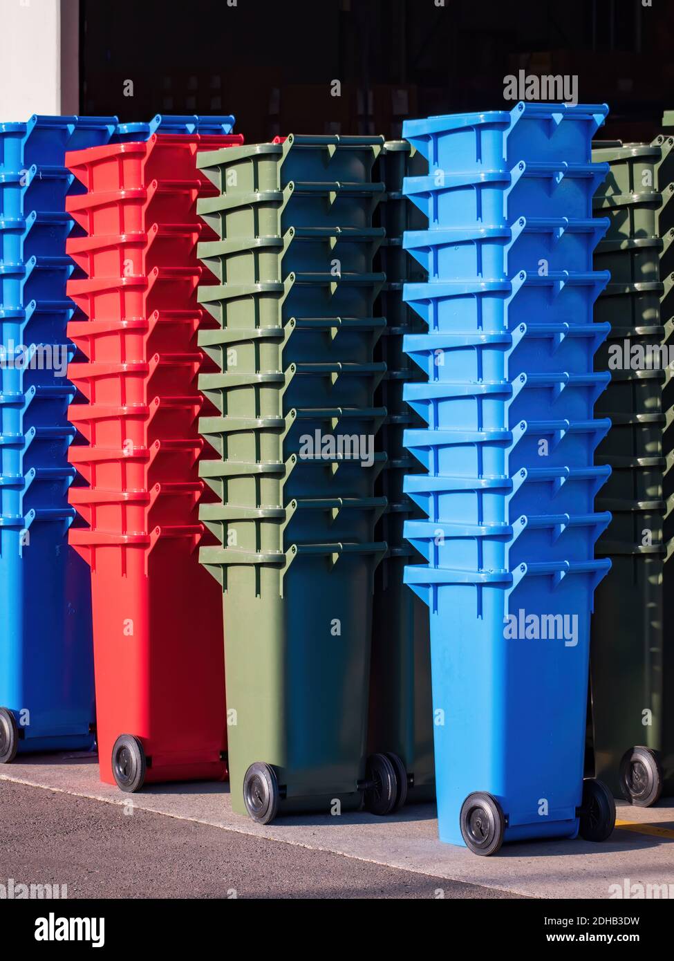 View of stacked new green, red and blue wheelie bins Stock Photo - Alamy