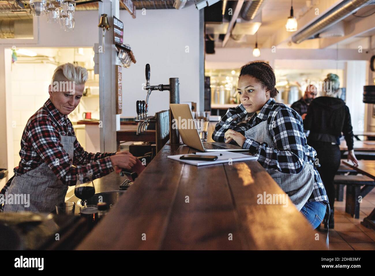 Woman using laptop while standing by partner at bar counter Stock Photo ...