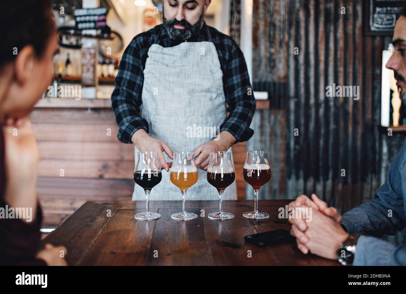 Bartender explaining about various craft beer to customers at bar Stock ...