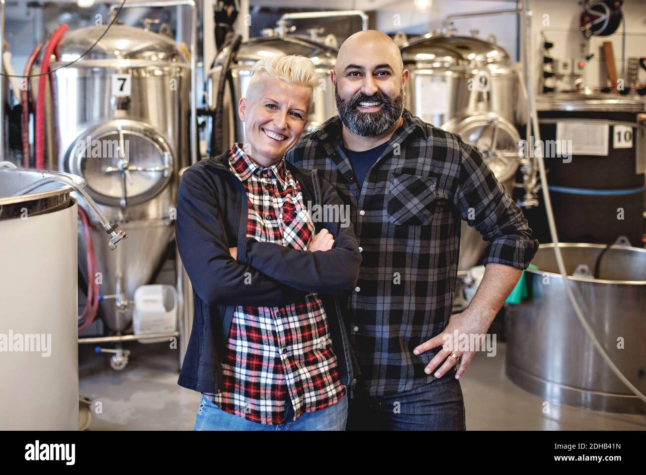 Portrait of smiling male and female partners standing in brewery Stock ...