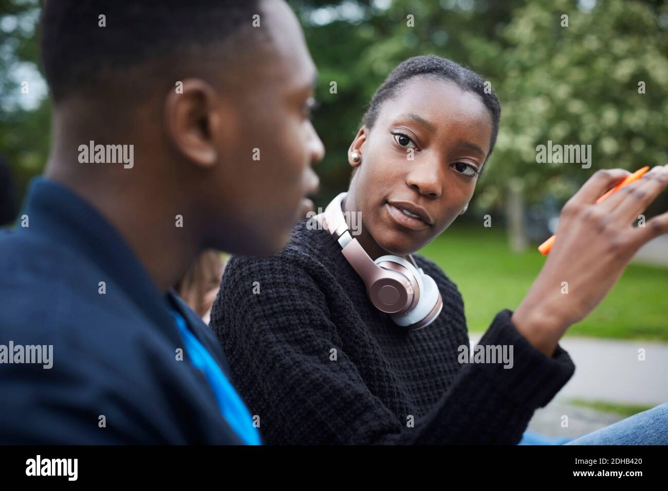 Teenage girl explaining male friend while studying at park Stock Photo ...