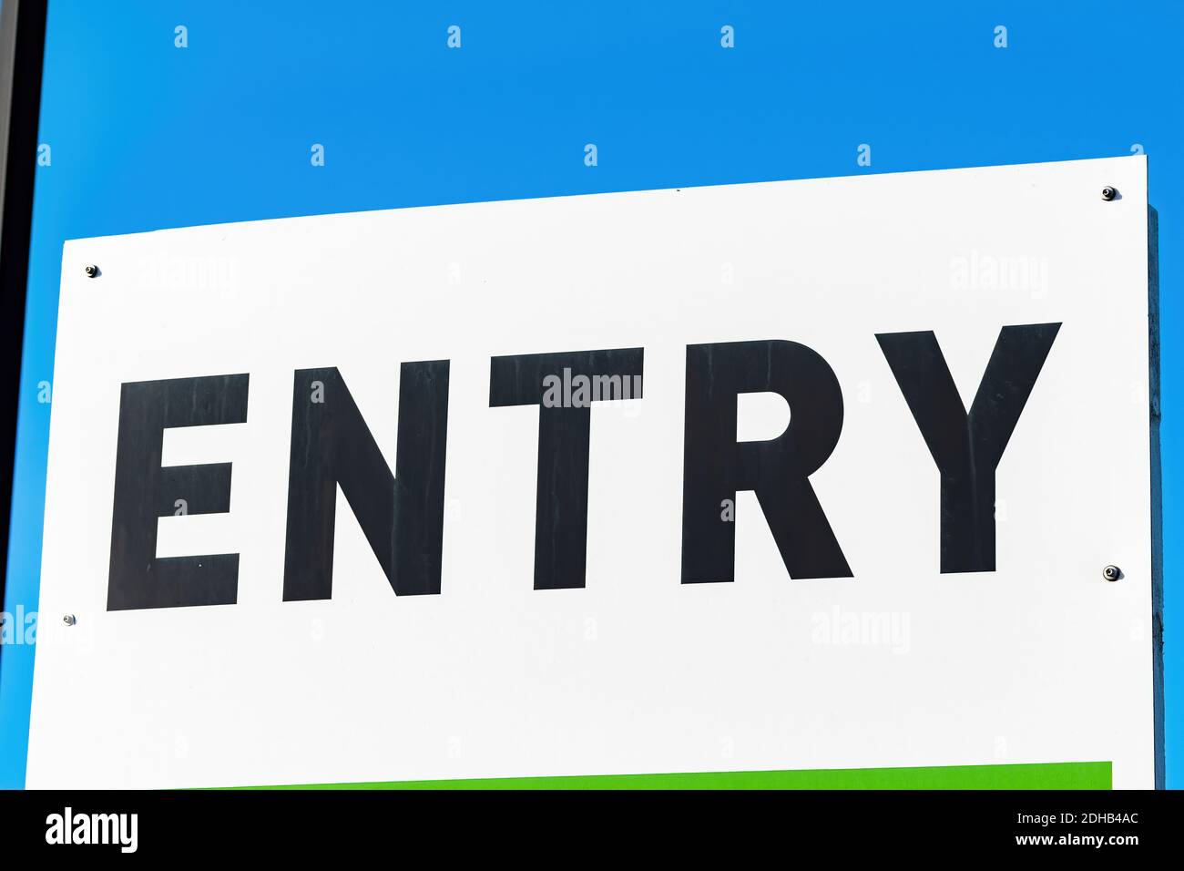 View of entry sign with black letters on white background and blue sky ...