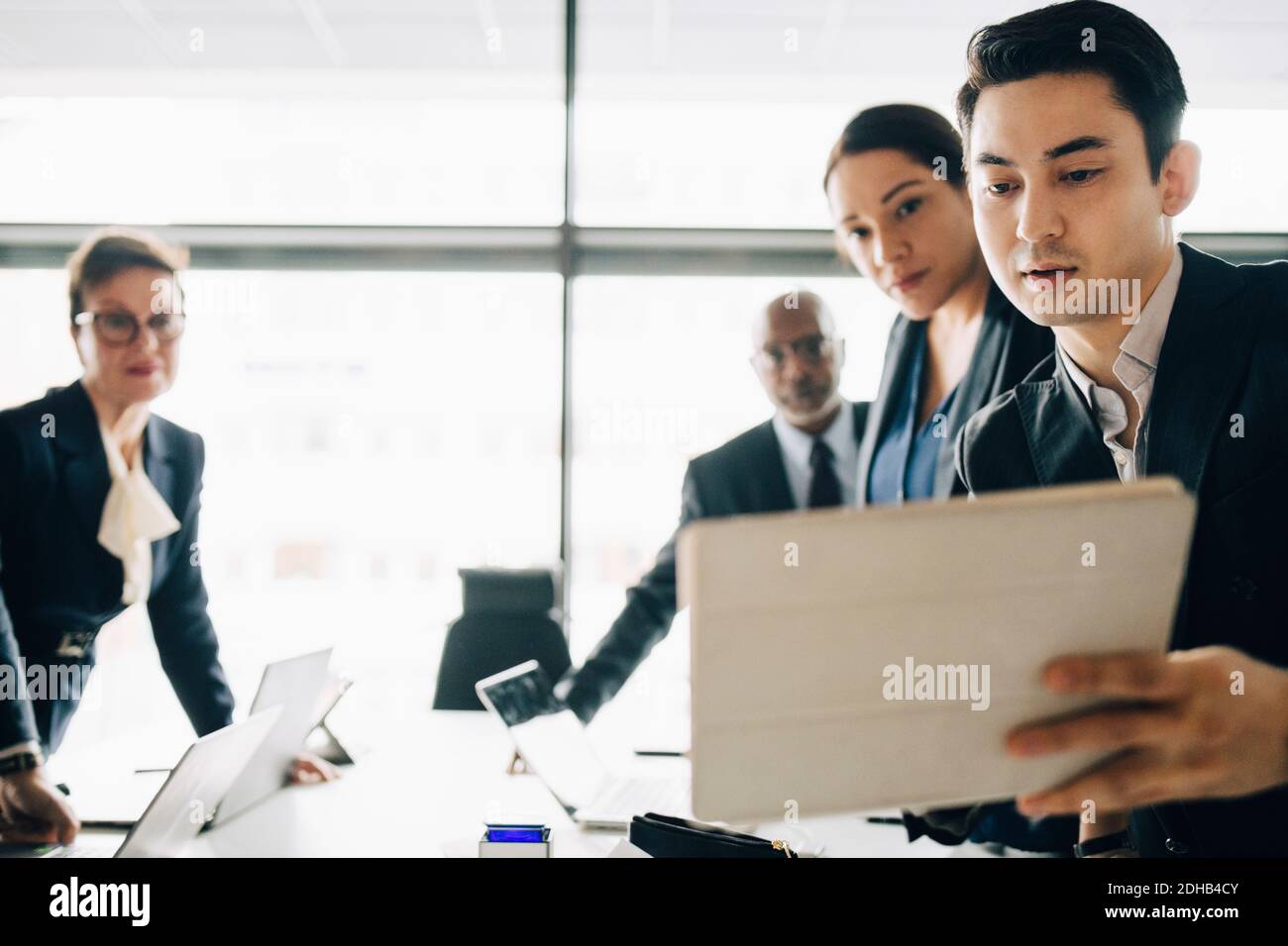 Young businessman explaining ideas to colleagues over digital tablet in ...