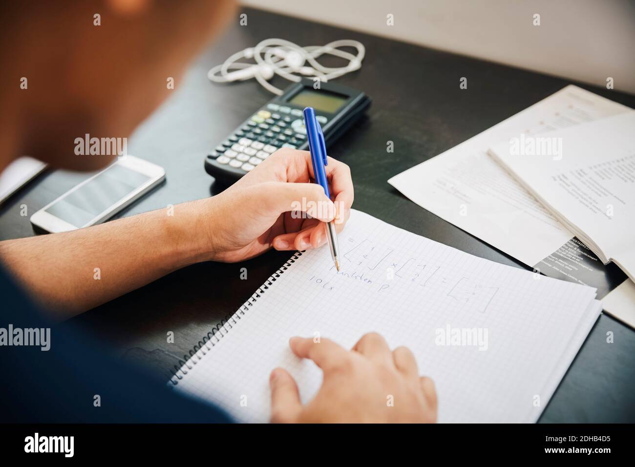 Cropped image young male university student writing in book at ...