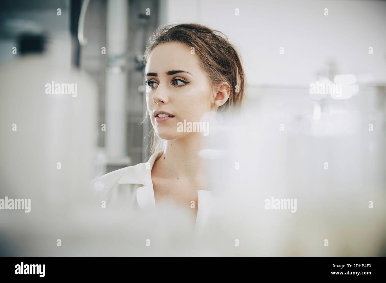 Confident young female student looking away while standing in ...