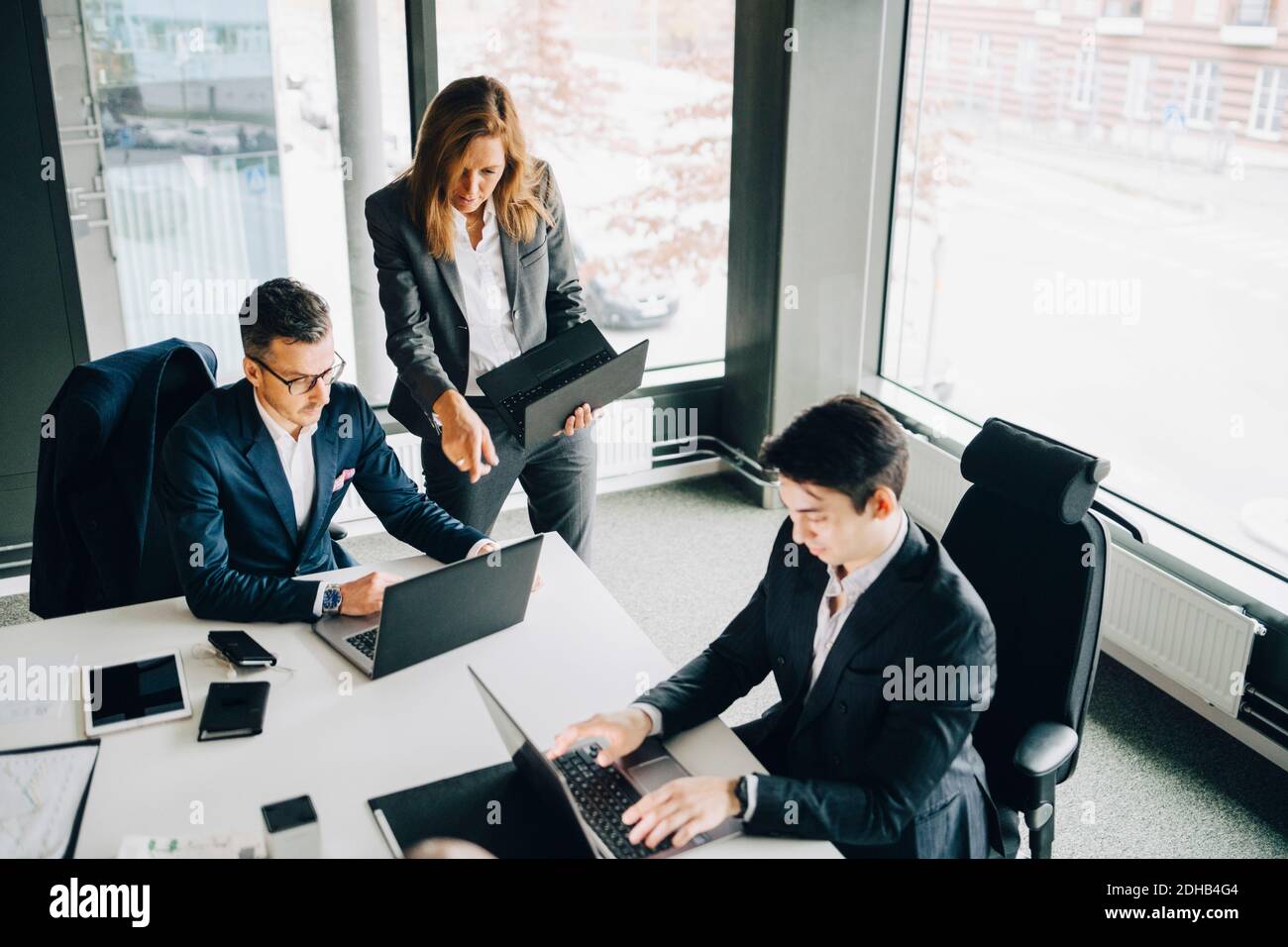 Female professional discussing with coworker over laptop while ...